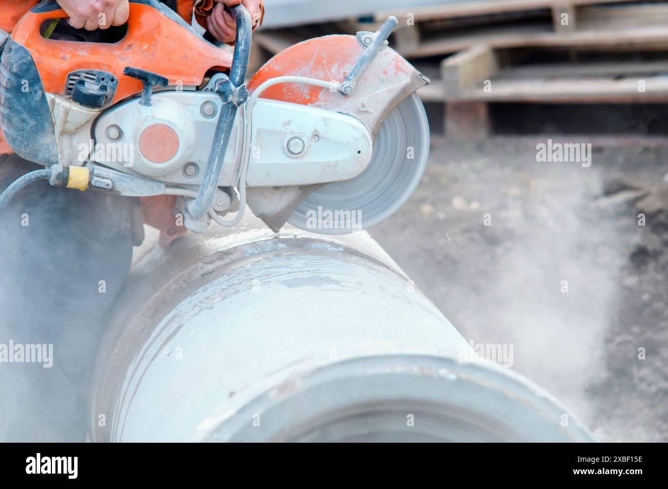 Construction worker cutting concrete pipe for drainage using a cut-off saw. Cutting concrete ...