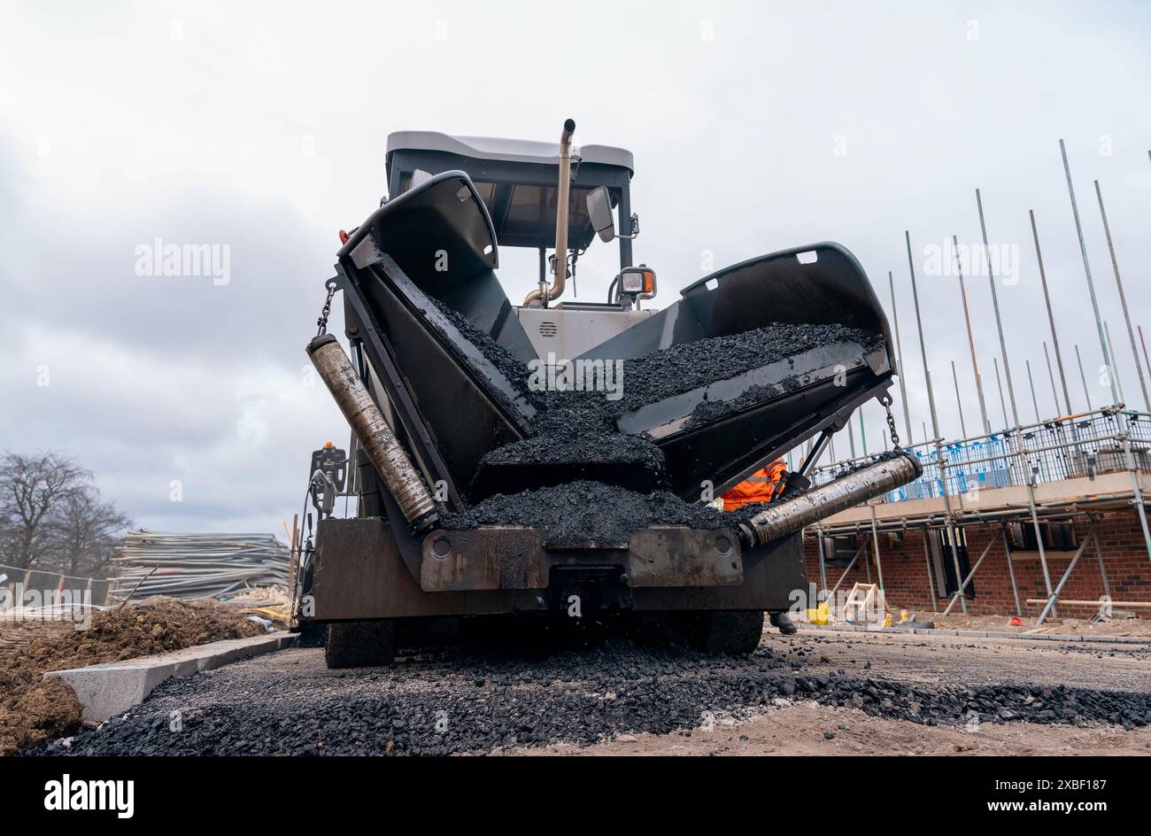 Asphalt paver filled with hot tarmac laying new road surface on new ...