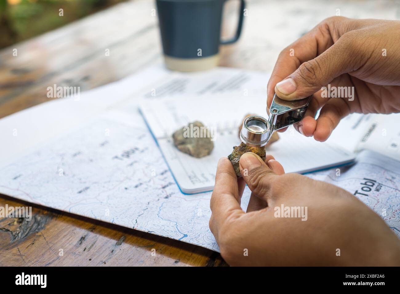 geologist using a loupe for rock and mineral identification and ...