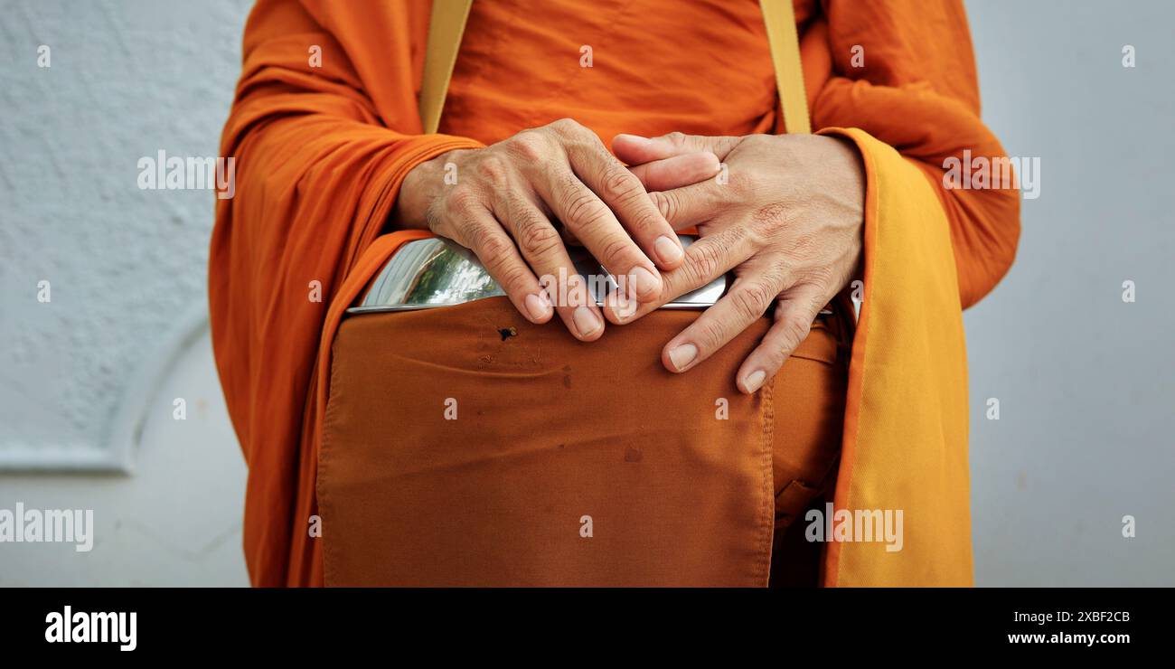 hand of monk dressing orange robe, holding bowl during reception of ...