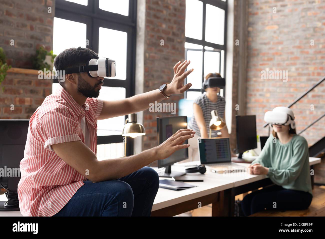 Diverse colleagues in office using vr headset. working on laptop in a ...
