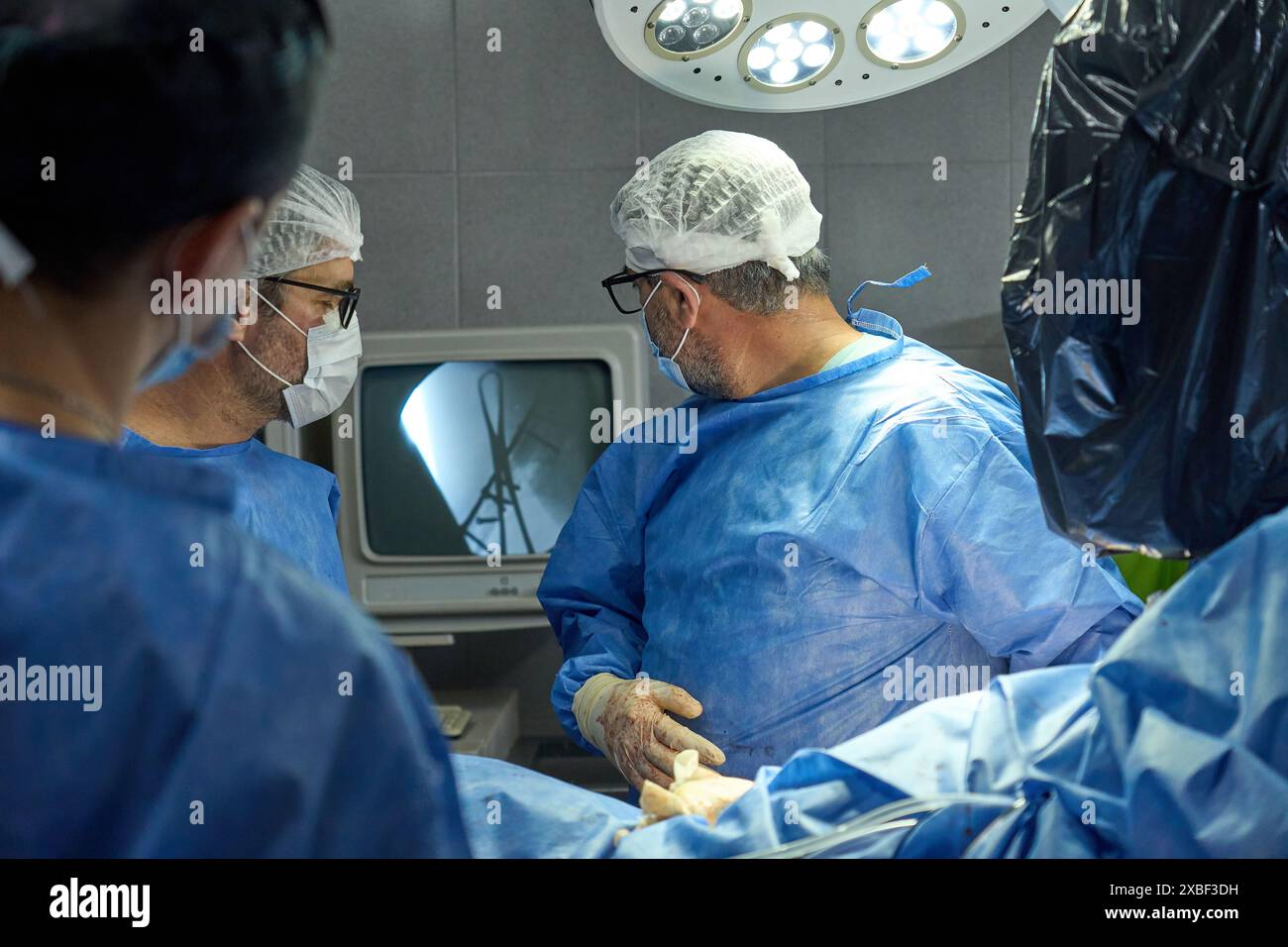 Surgeons looking at monitor and discussing procedure in operating room ...