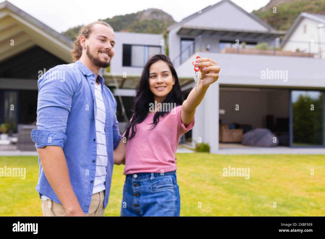 Young diverse couple are smiling while holding house keys, buying first ...
