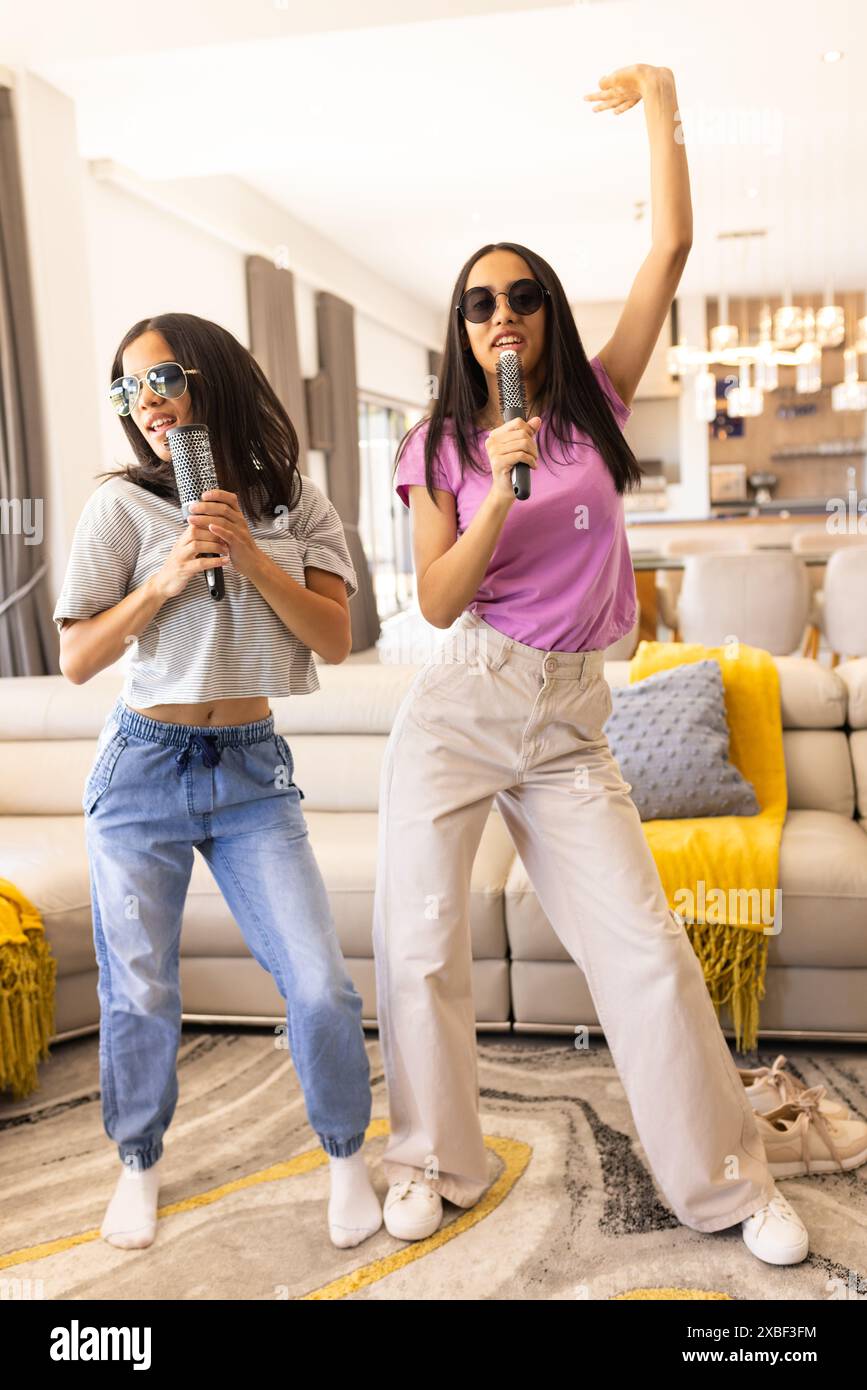 Two biracial young sisters sing karaoke together in casual outfits and ...