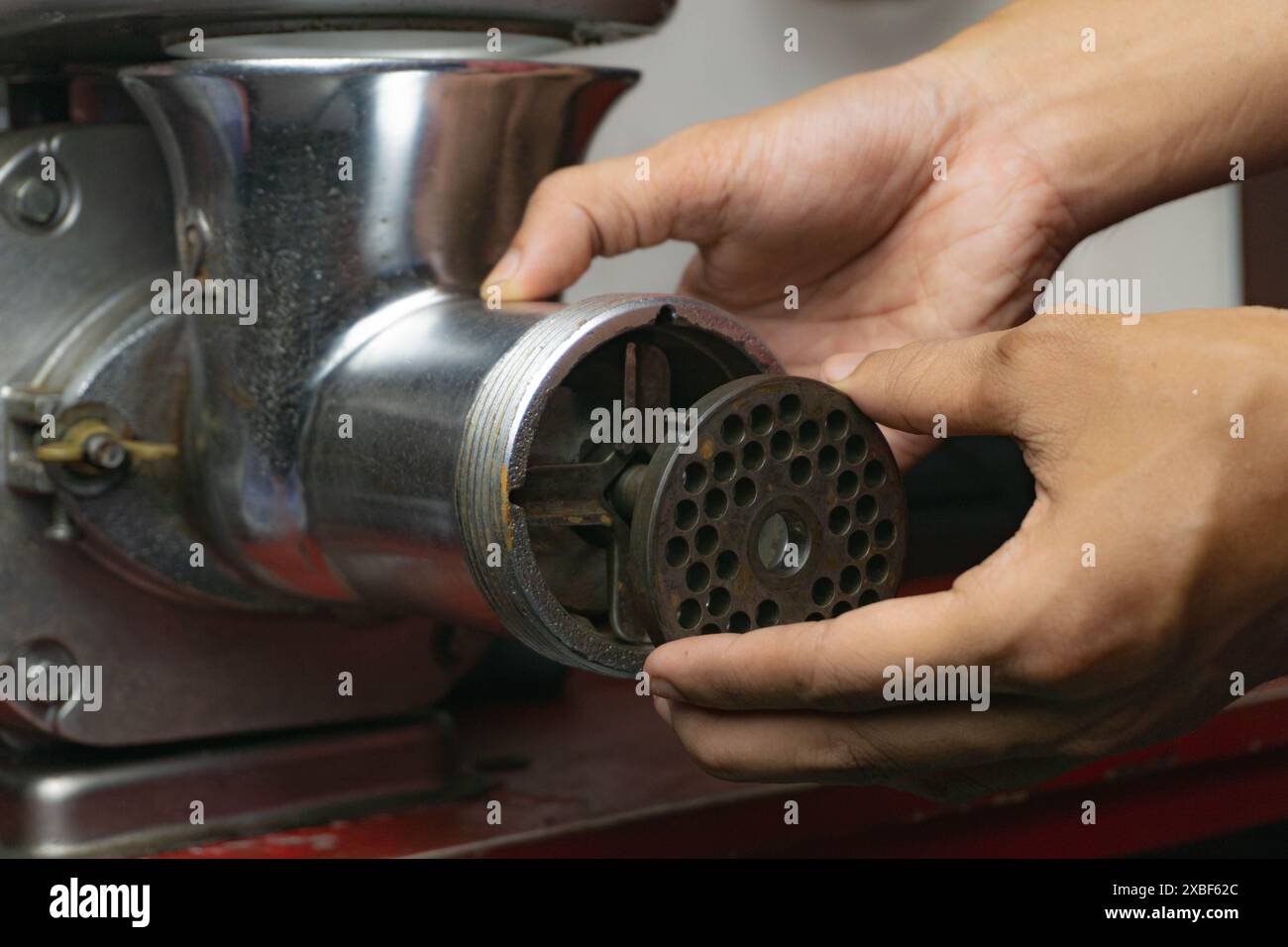 a man attaching grinder plate to a meat grinder Stock Photo - Alamy