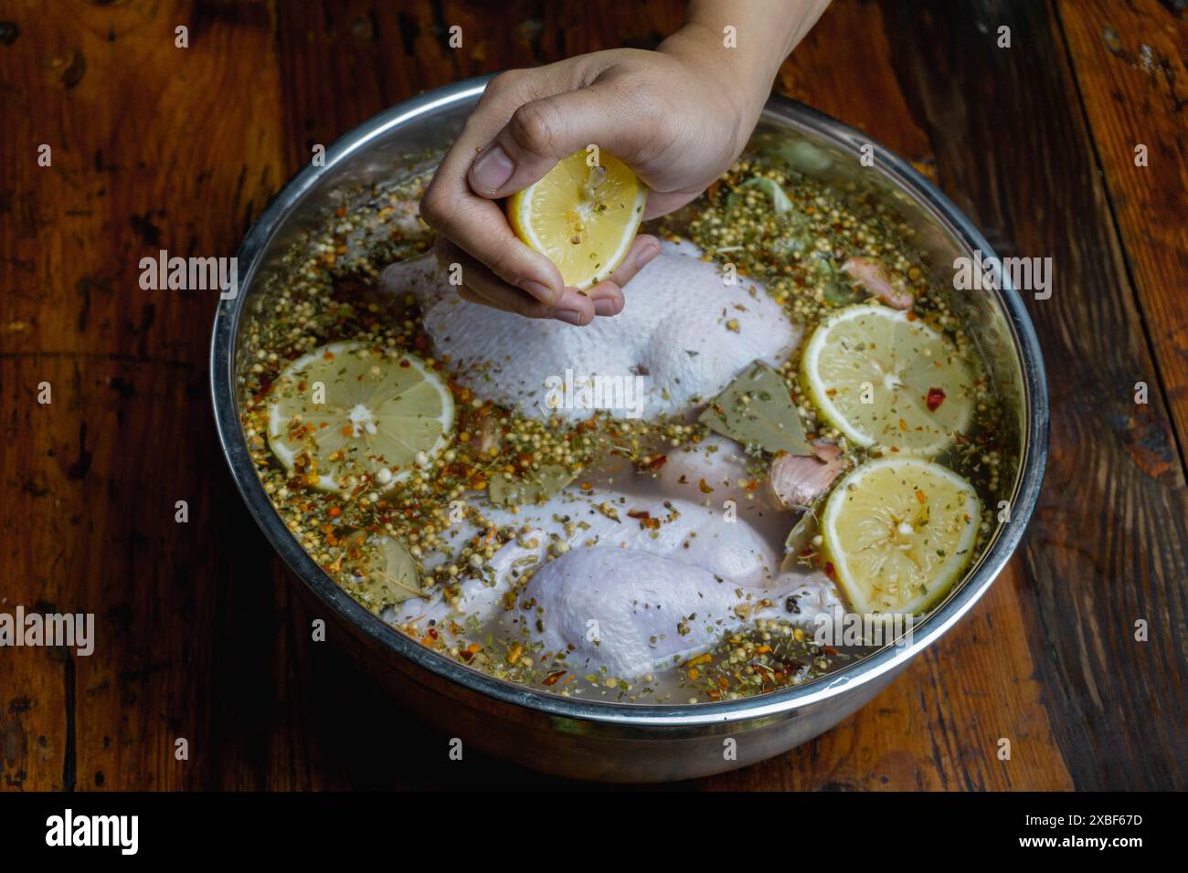 male hand squishing fresh lemon to salt water brine, adding flavor and ...