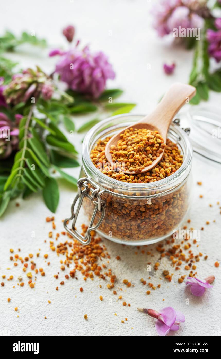 Healthy bee pollen grains. Bee pollen on a glass jar and acacia flowers ...