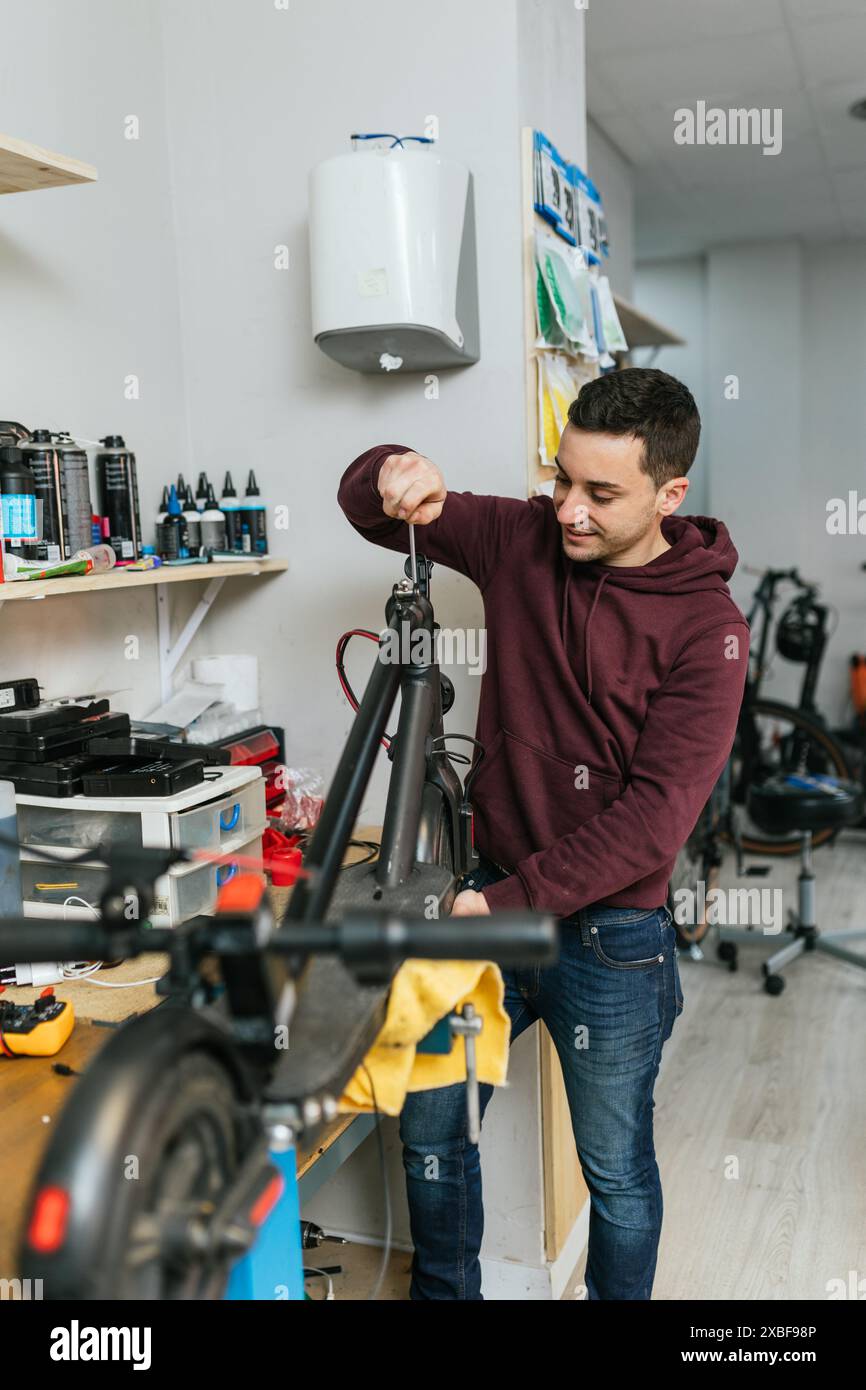 Vertical photo of a mechanic repairing an electric scooter Stock Photo ...