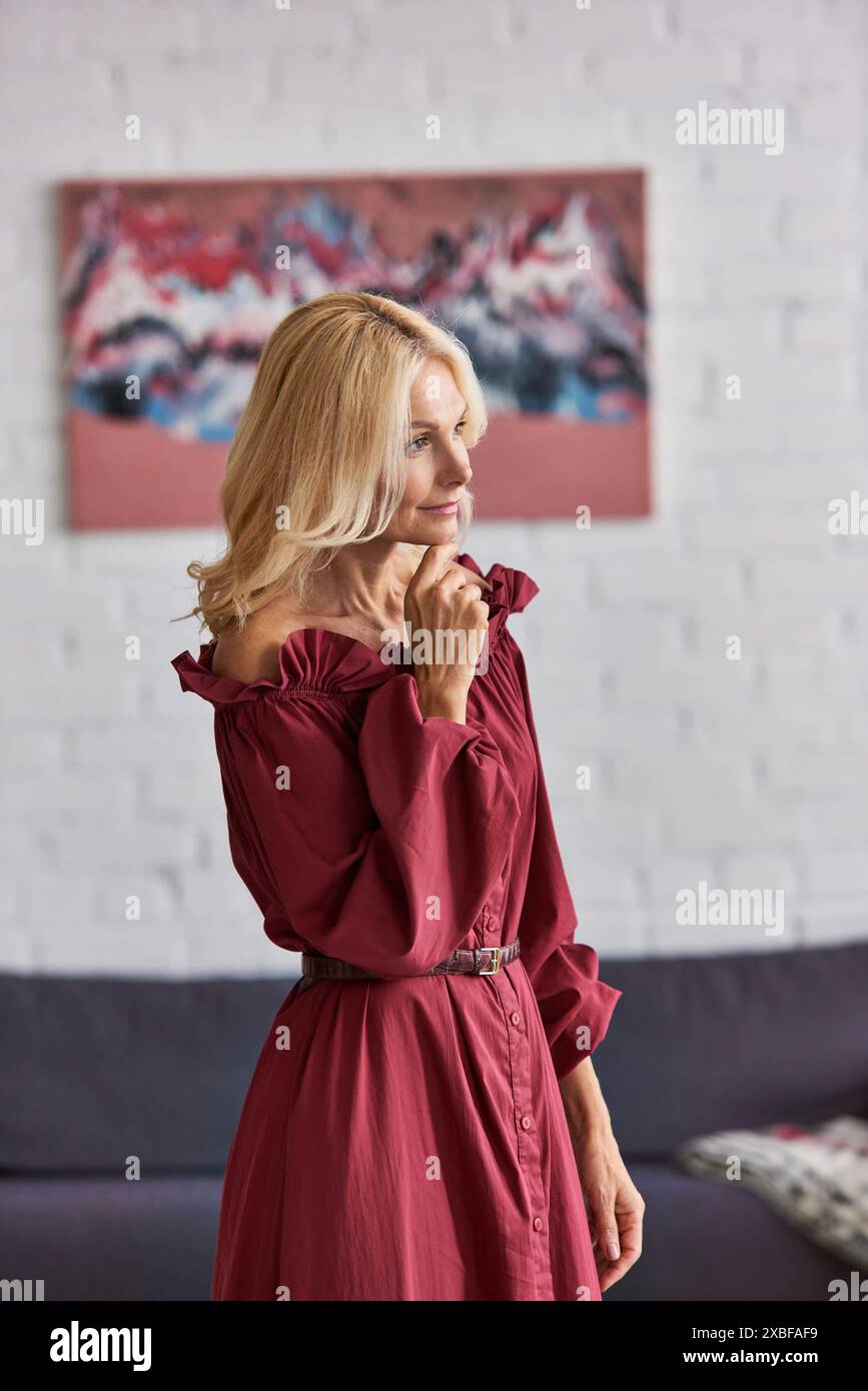 A mature woman in a striking red dress stands gracefully in a cozy ...