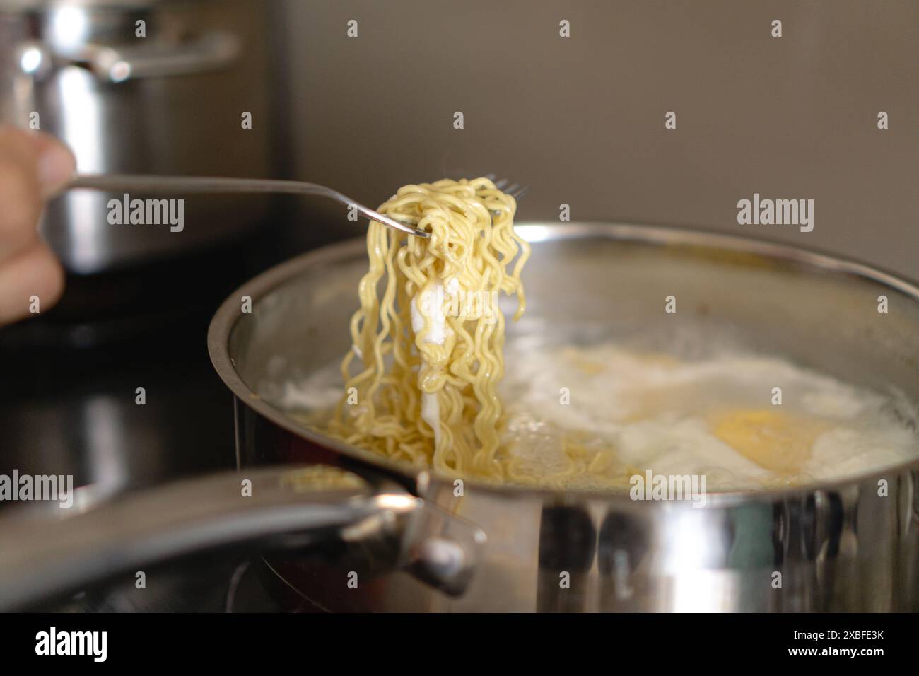 cooking instant noodle with an egg, in the stainless pan Stock Photo ...