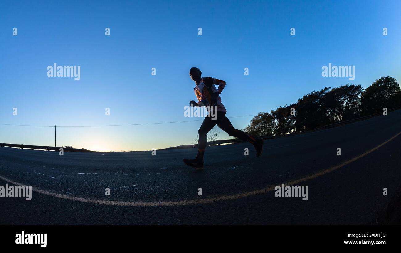 Marathon runners silhouetted morning dawn sunrise running up hill in ...