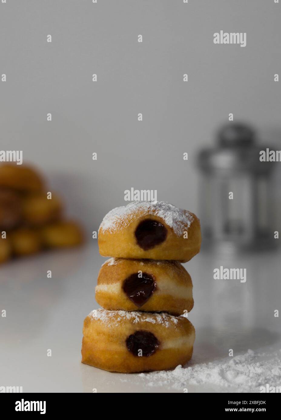 A stack of three jelly-filled doughnuts dusted with powdered sugar on a ...