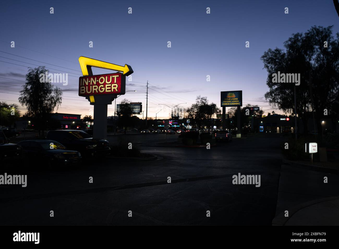 The In-N-Out Burger sign illuminated at dusk in a parking lot with ...