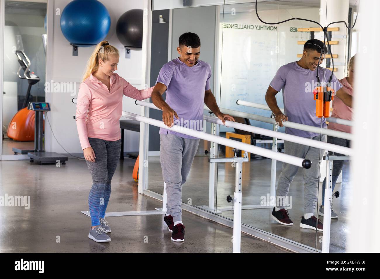 A biracial man is practicing walking with support from female physical ...
