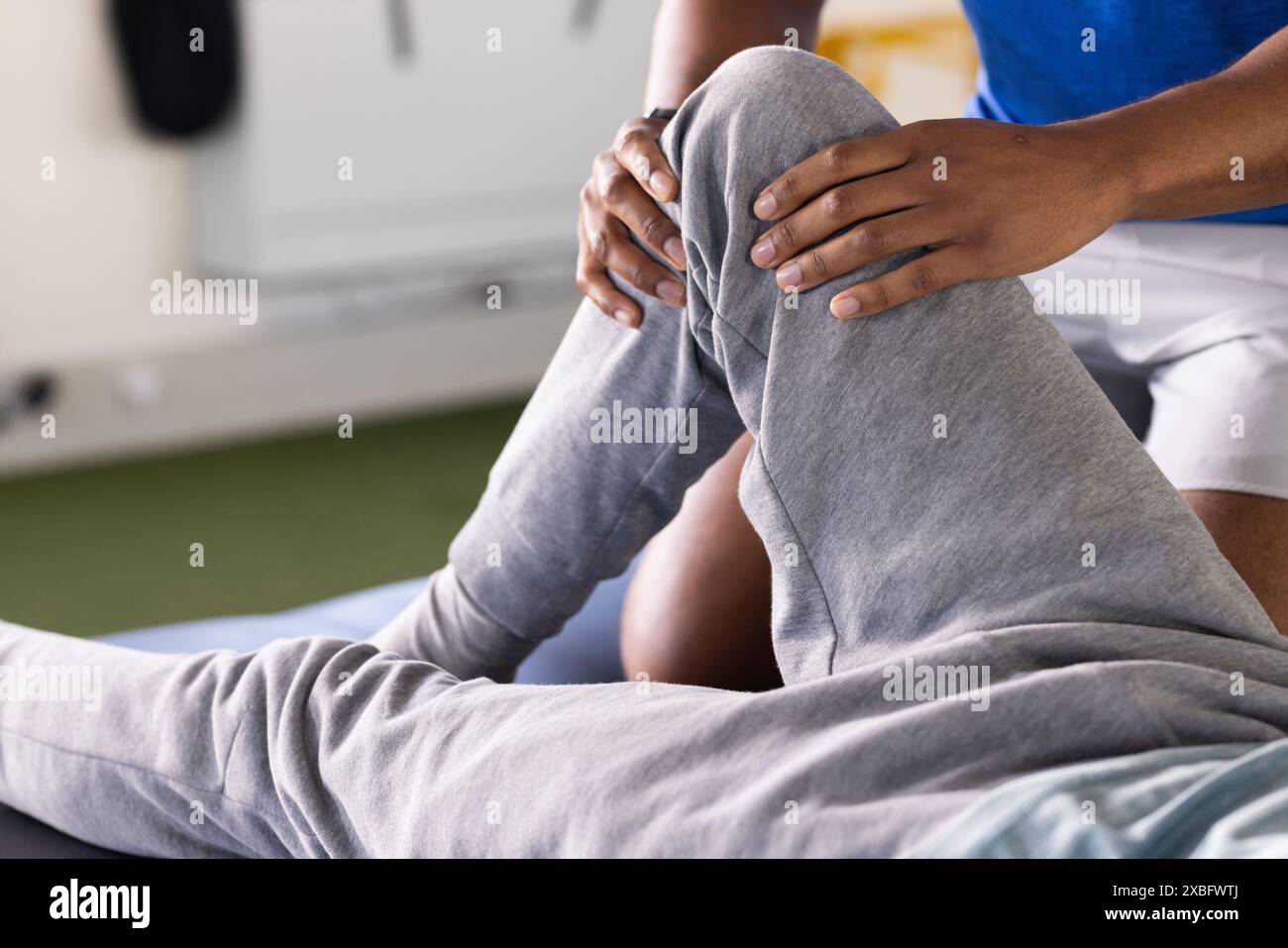 Biracial man receiving physical therapy for his leg in medical facility ...