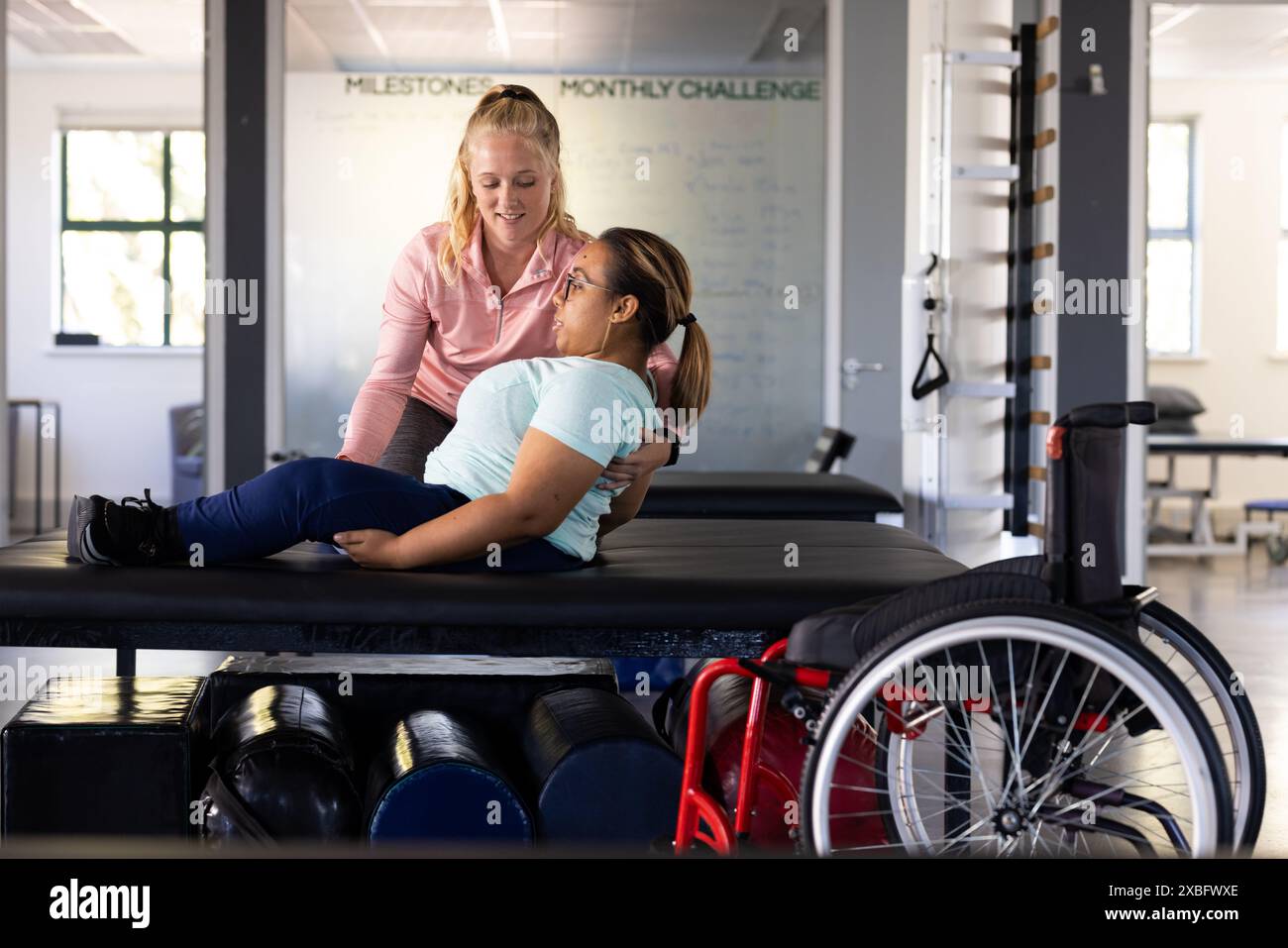 Quadriplegic biracial woman aids female physical therapist at rehab ...