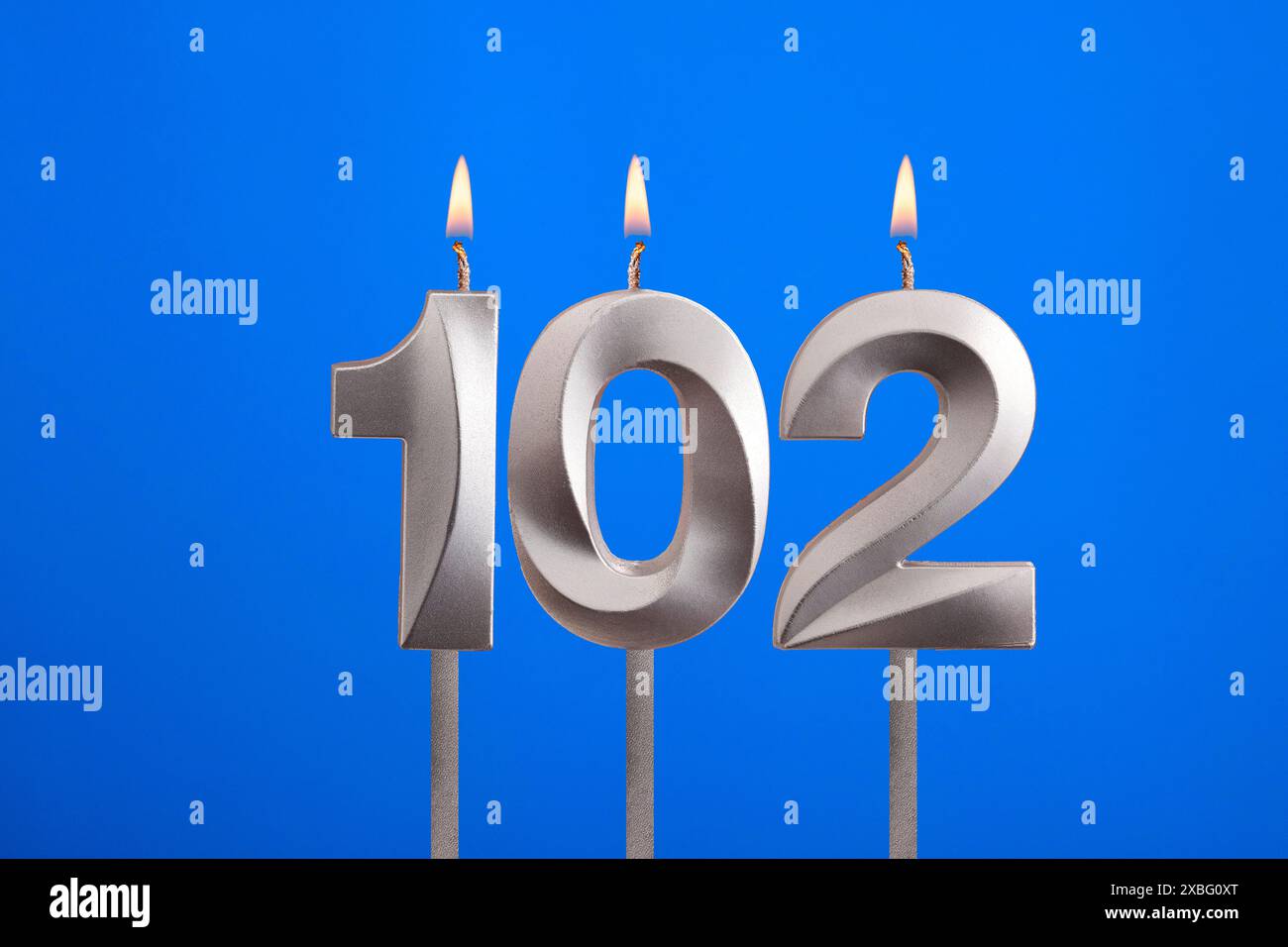 Birthday number 102 - Candle lit on blue background Stock Photo - Alamy