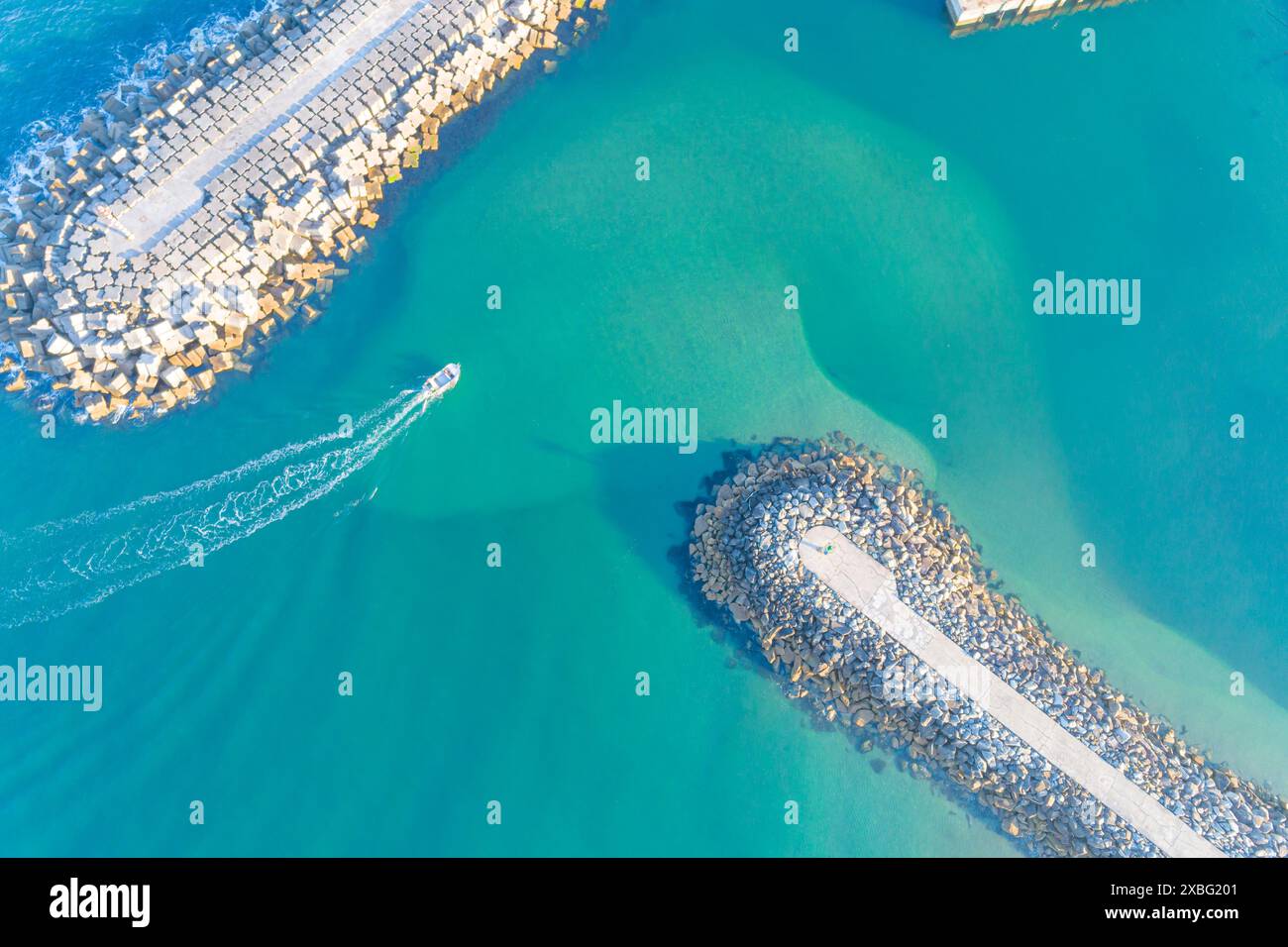 aerial top view of a fishing boat entering a harbor protected by ...