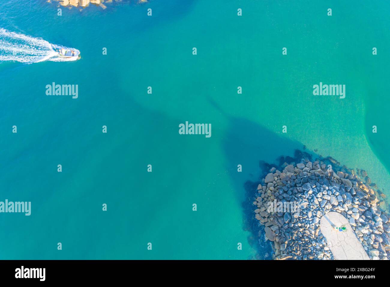 aerial directly above view of a fishing boat entering a harbor ...