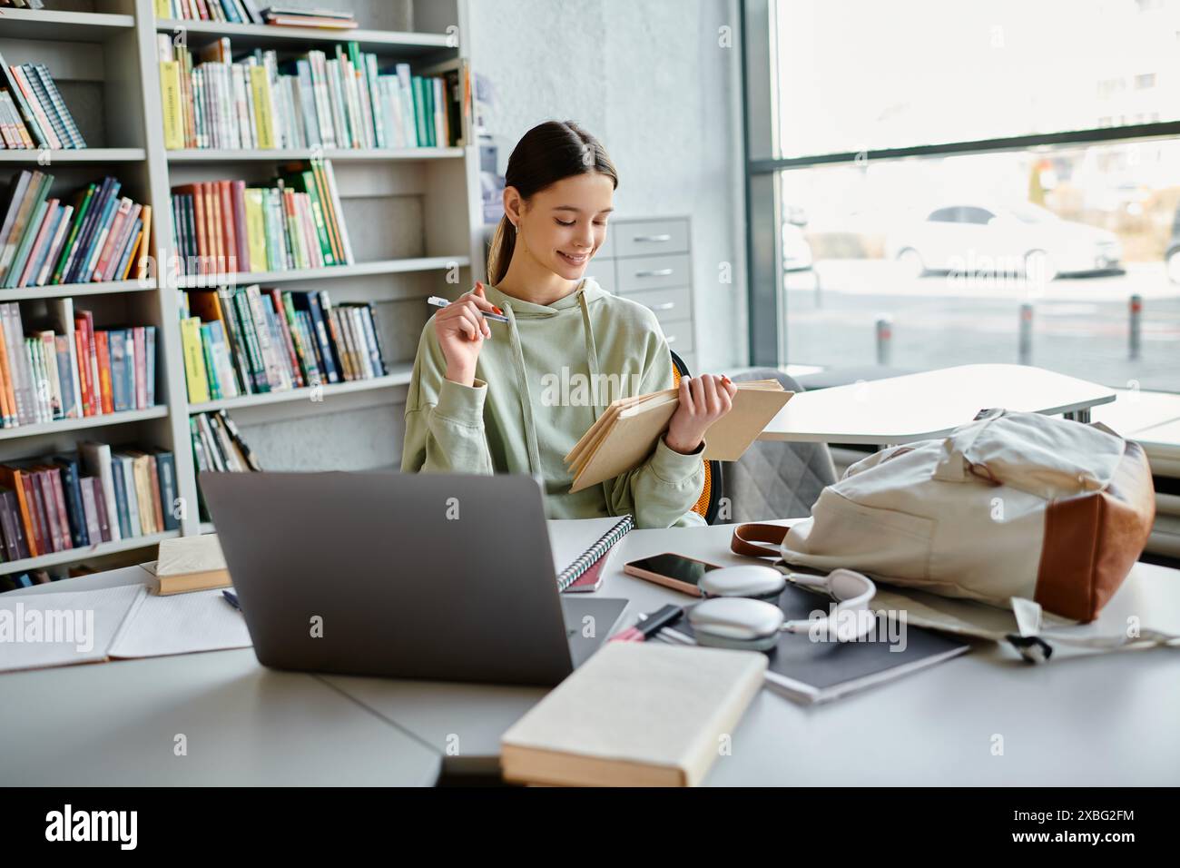 A teenage girl engrossed in homework on a laptop, seated at a desk next ...
