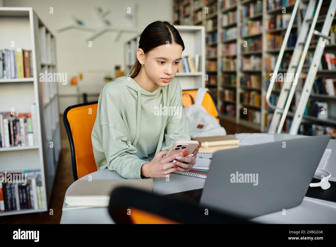 A teenage girl sits at a desk, focusing on homework on her laptop and ...