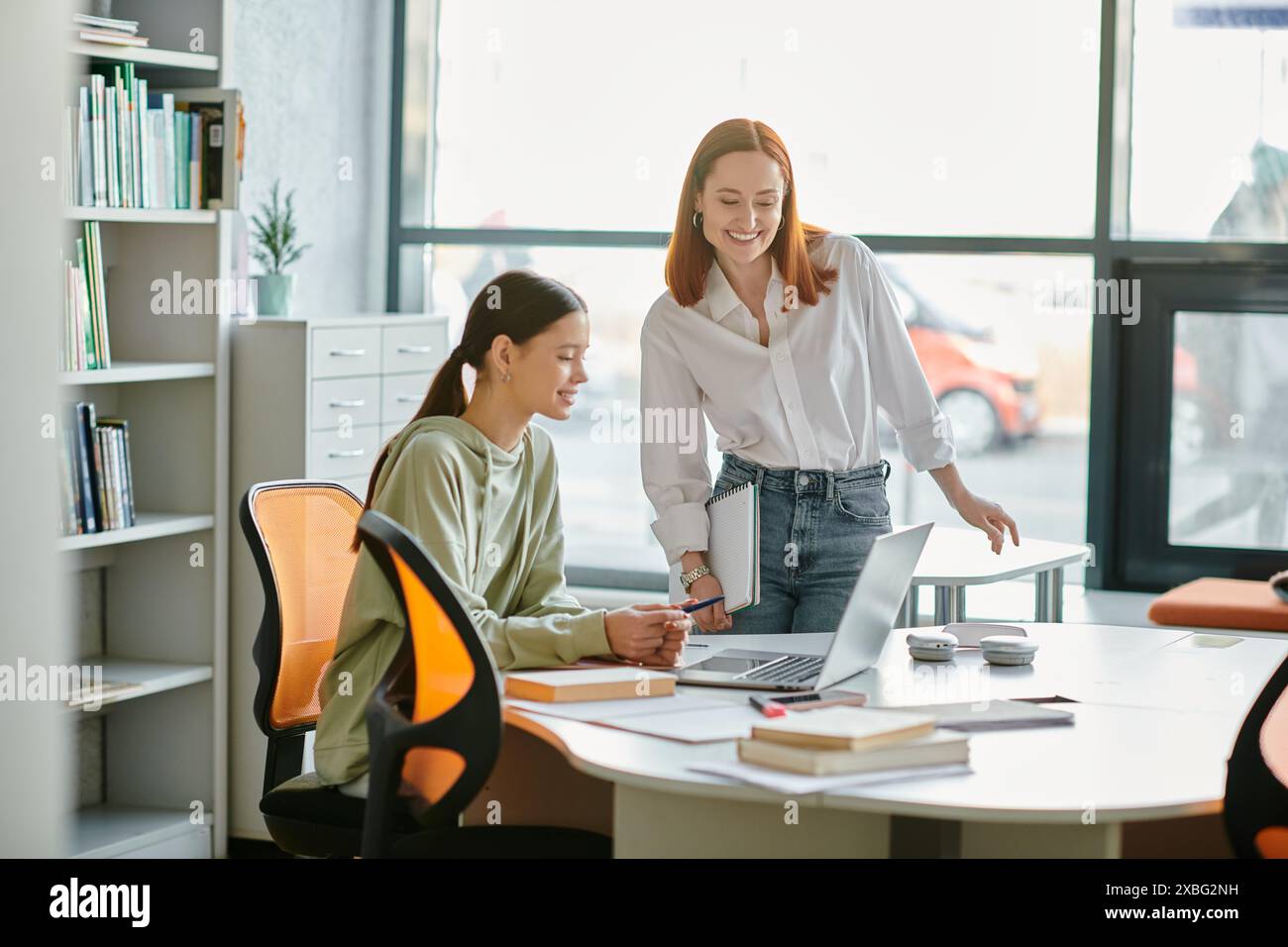 A redhead tutor guides a teenage student through after-school lessons ...