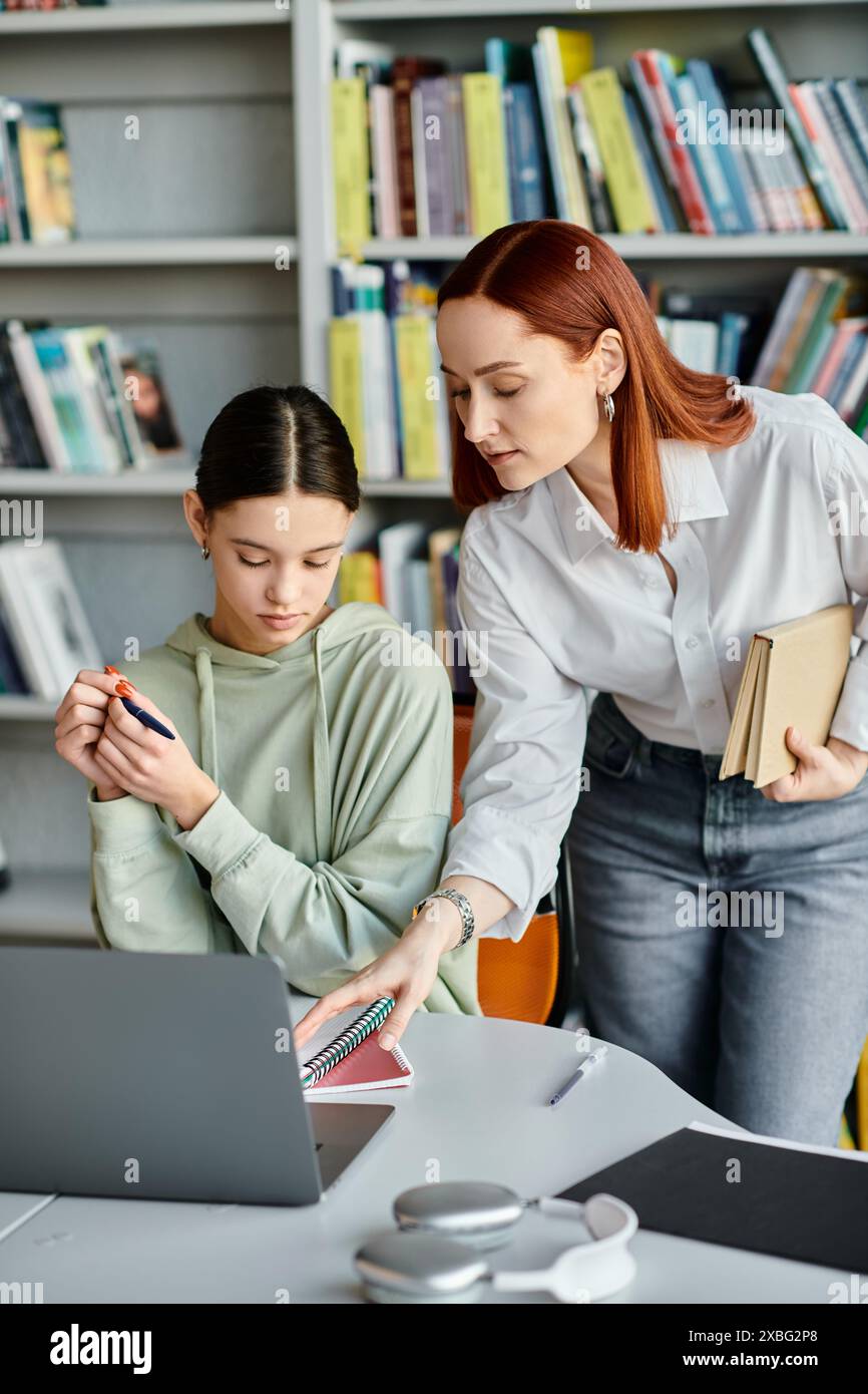A redheaded tutor teaches a teenage student in a library, both focused ...