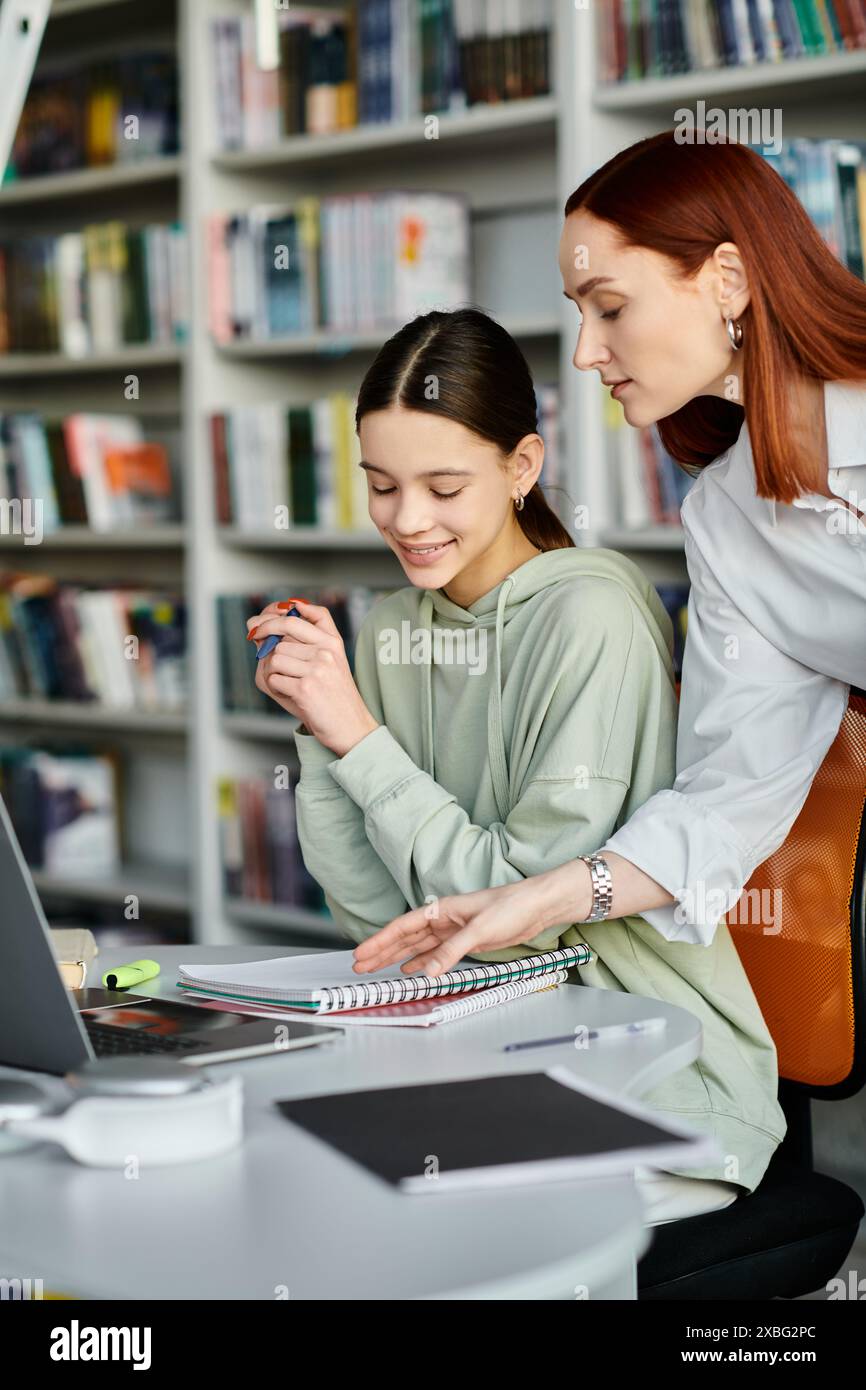 A tutor with red hair teaches a teenage girl in a library, as they work ...