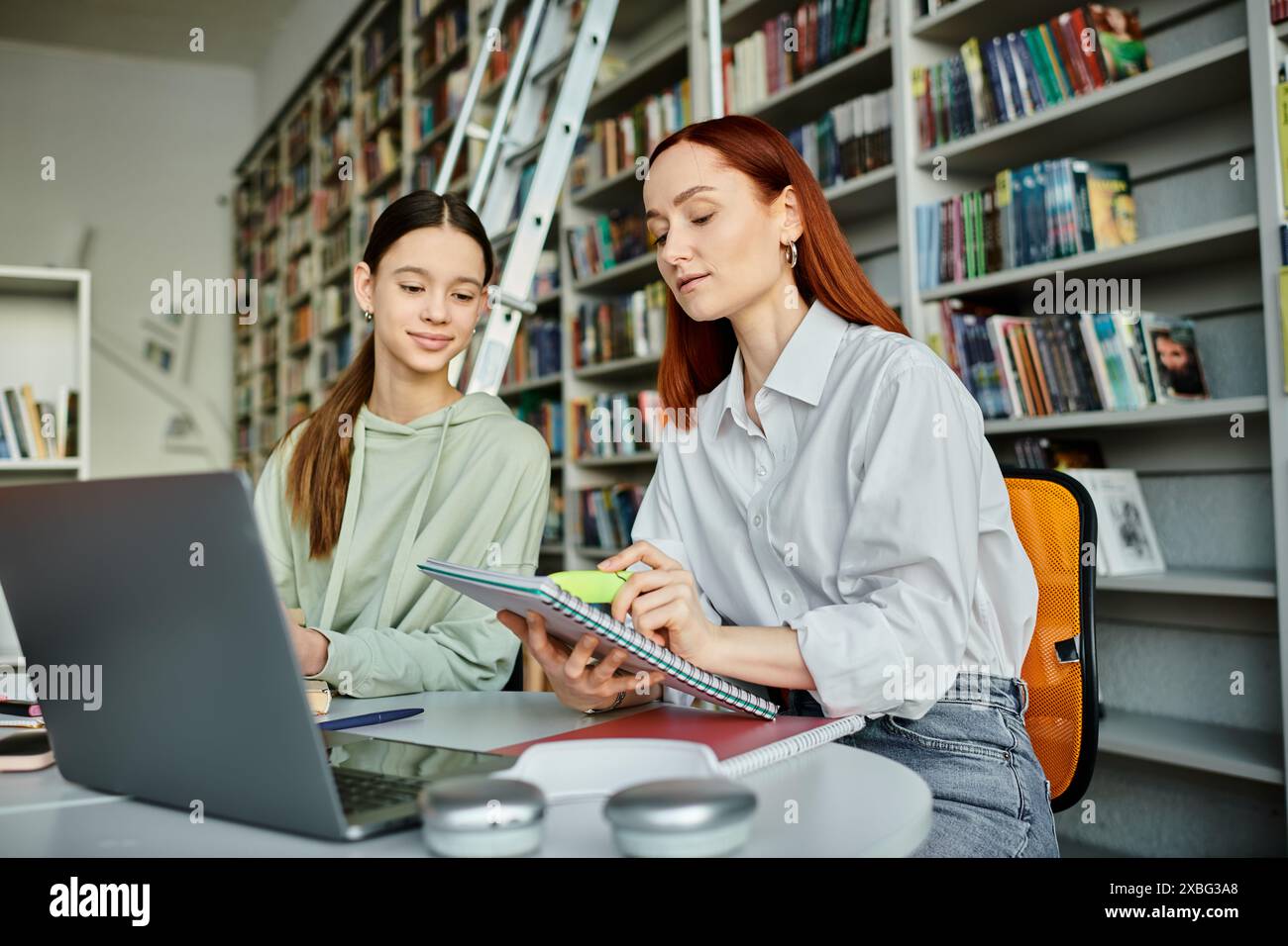 Tutoring session in the library, a redhead tutor and a teenage girl ...