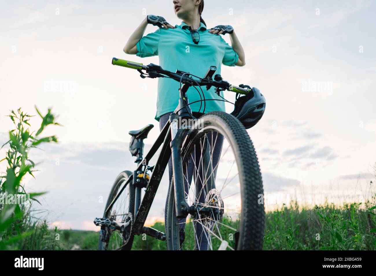 Woman Stretching Before Bike Ride in Green Field Stock Photo - Alamy
