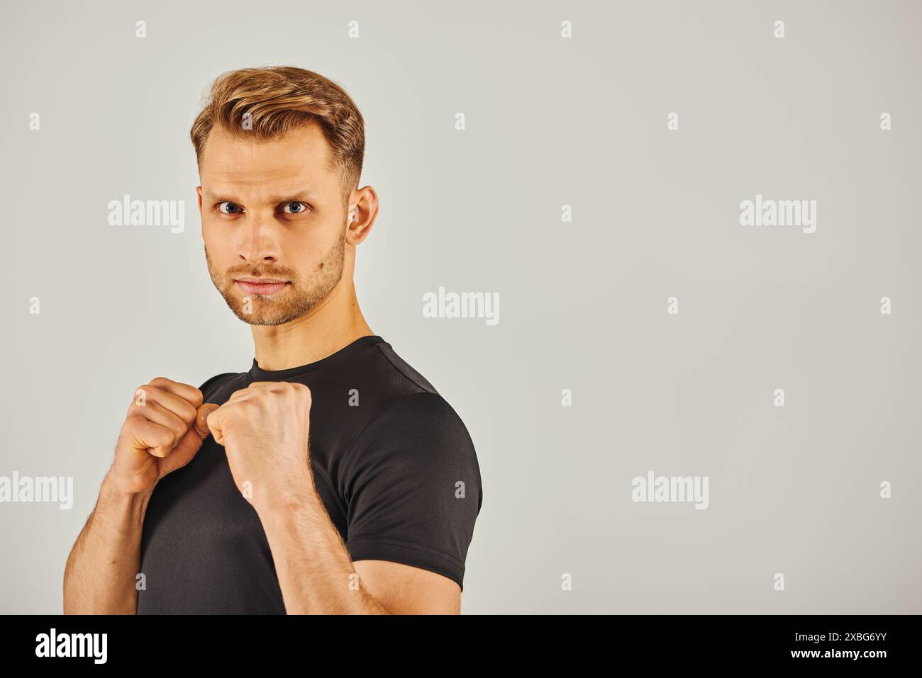 A young athletic man in active wear confidently poses with his fists ...