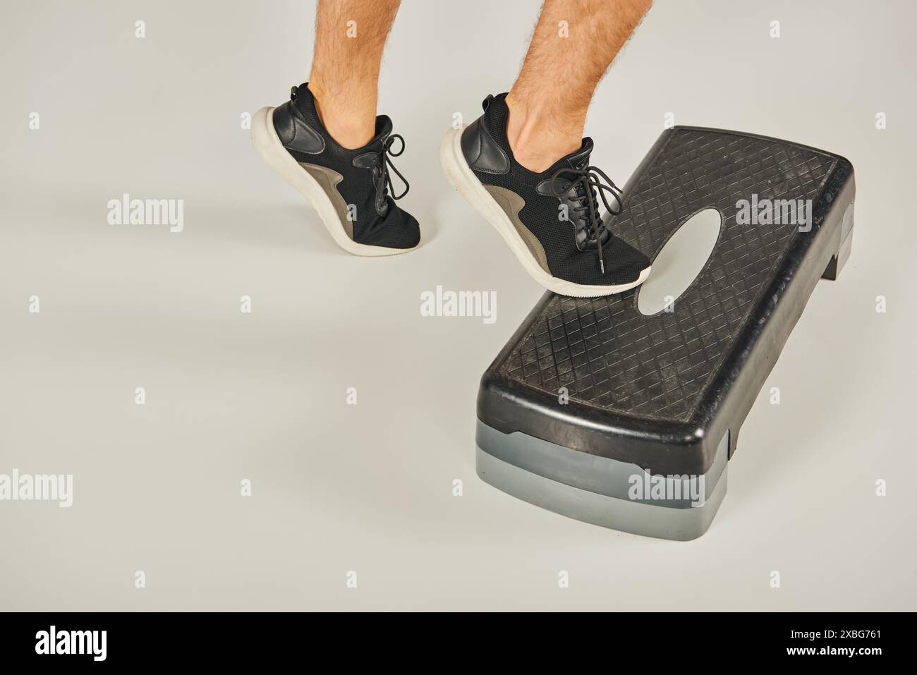 A man in active wear stands confidently atop a step stool against a ...