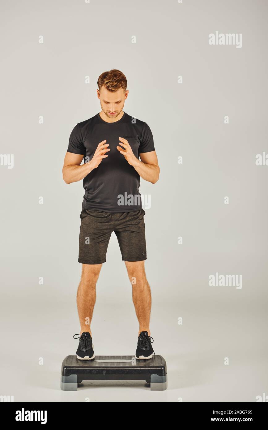 A young sportsman in active wear challenges his balance on a stepper in ...
