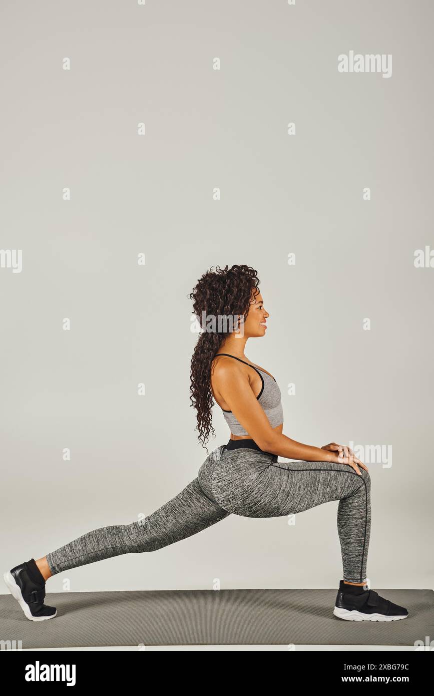 Curly African American sportswoman in active wear performing a squat ...