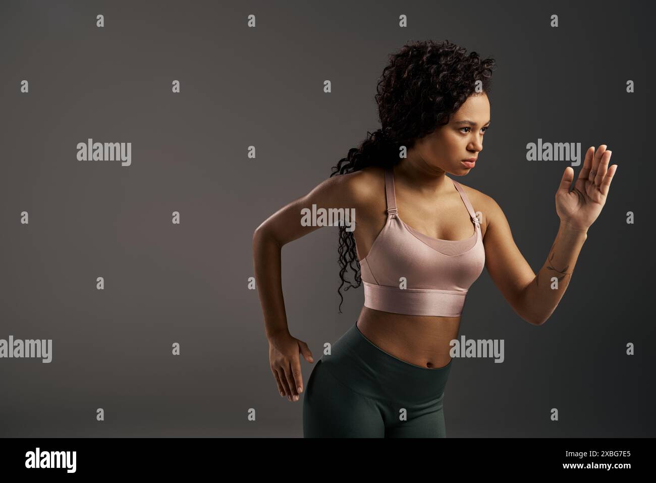 Curly African American sportswoman in sports bra and leggings striking ...