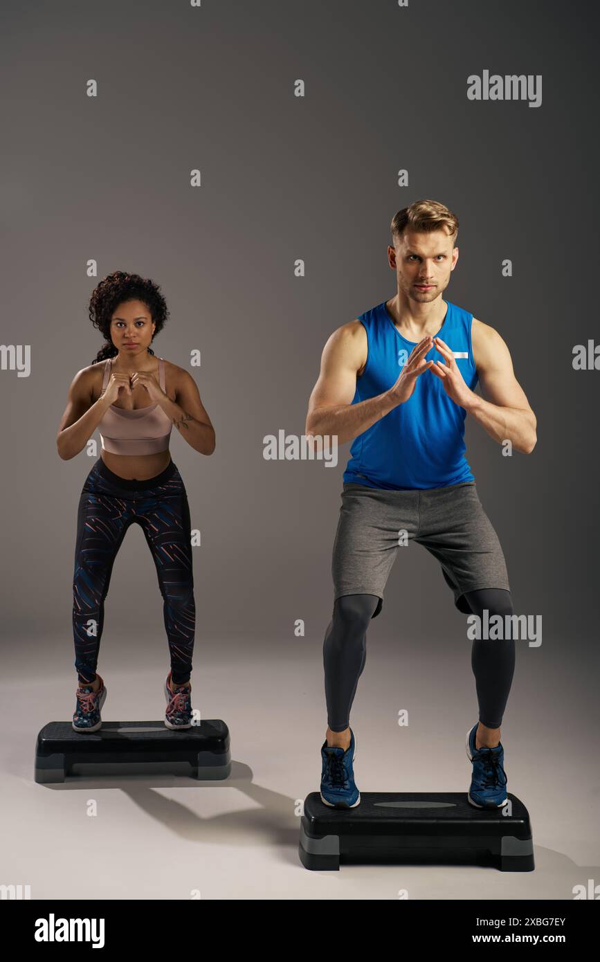 Multicultural, fit couple in active wear working out on steppers in a ...