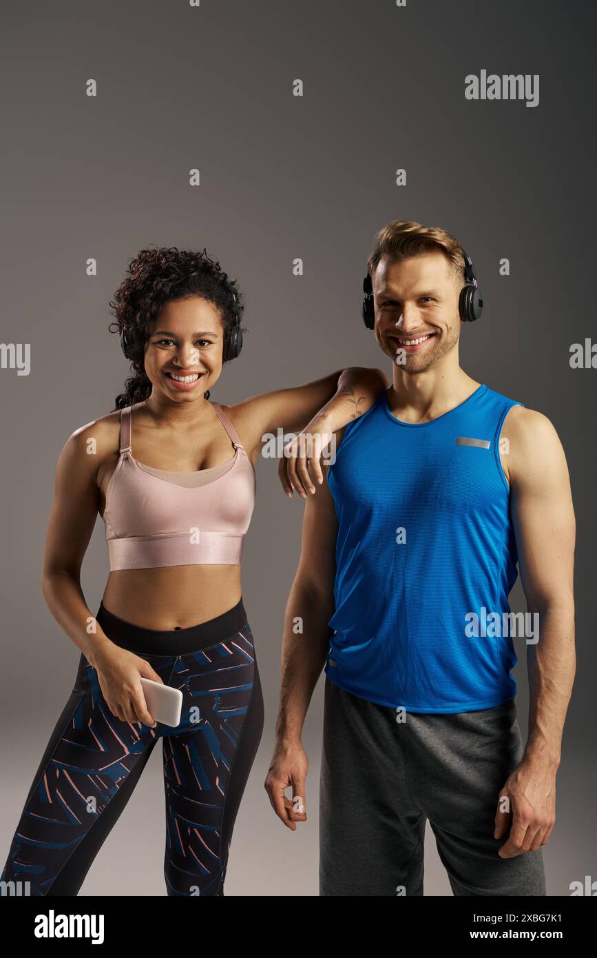 A fit multicultural couple in activewear strikes a pose together in a ...