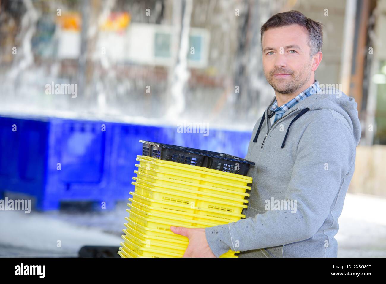 Portrait of man carrying stack of crates Stock Photo - Alamy