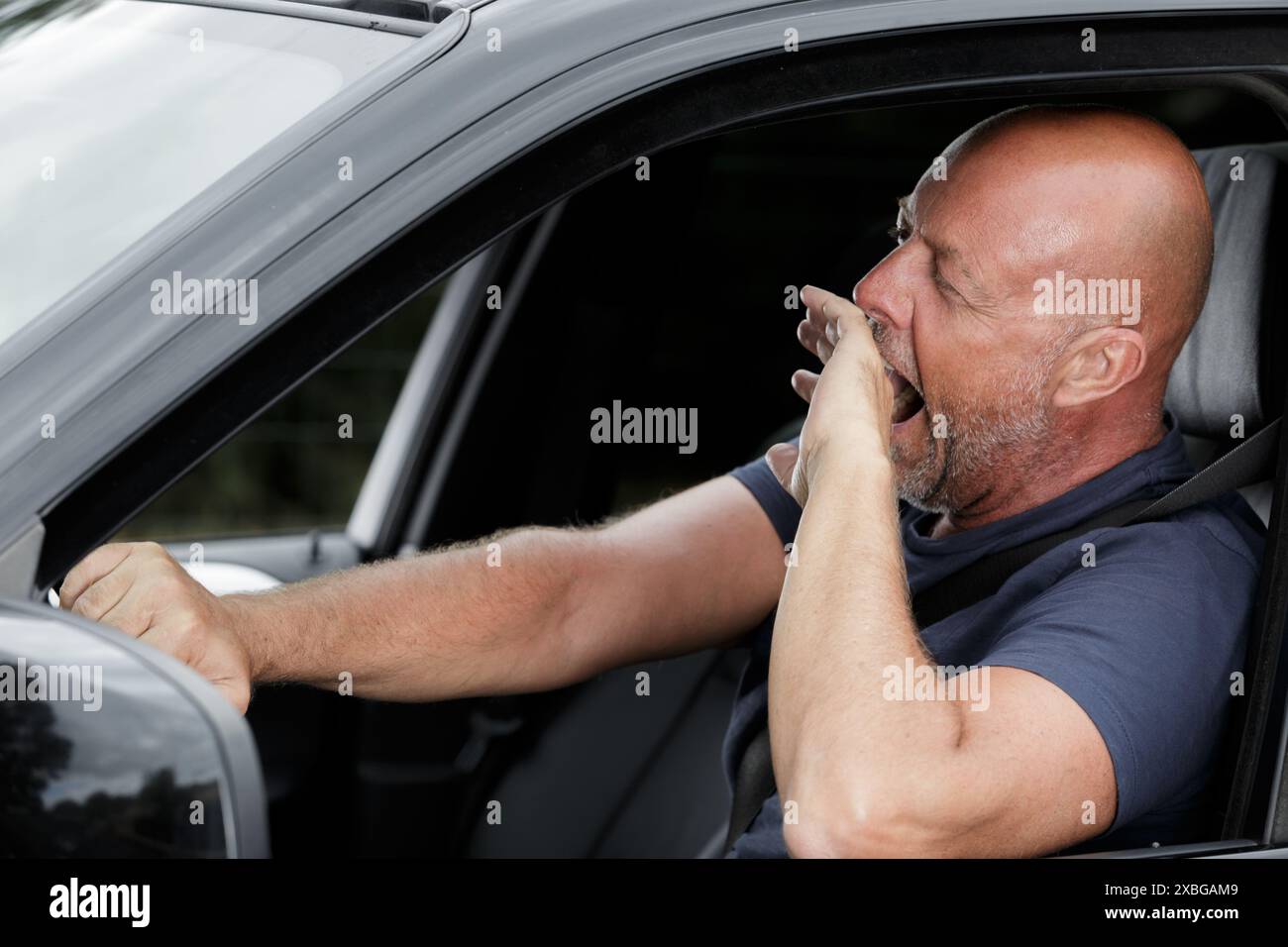 side view of a mature man yawning while driving car Stock Photo - Alamy