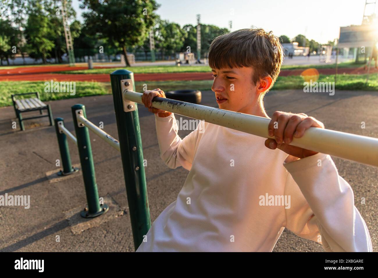 A young boy is standing with a baseball bat held casually over his ...