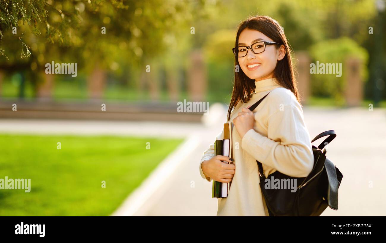 Young Student Walking Through Campus Pathway With Books Stock Photo - Alamy