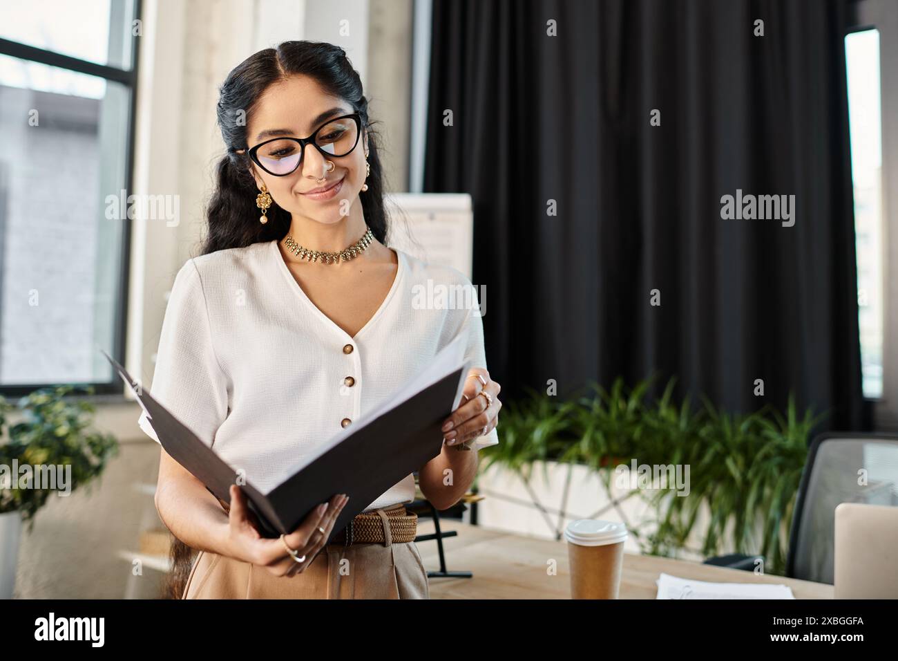 A dynamic indian woman with glasses handling a folder in a professional ...