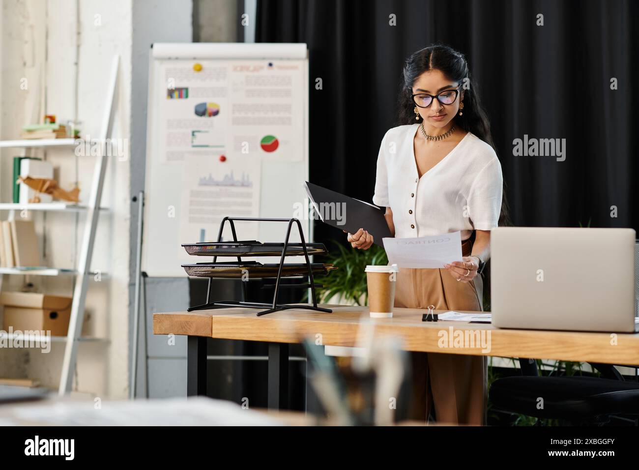 A stylish young indian woman stands confidently in an office setting ...