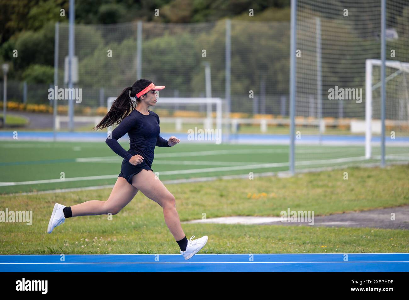 copyspace determined Latina woman athlete races down the blue track ...