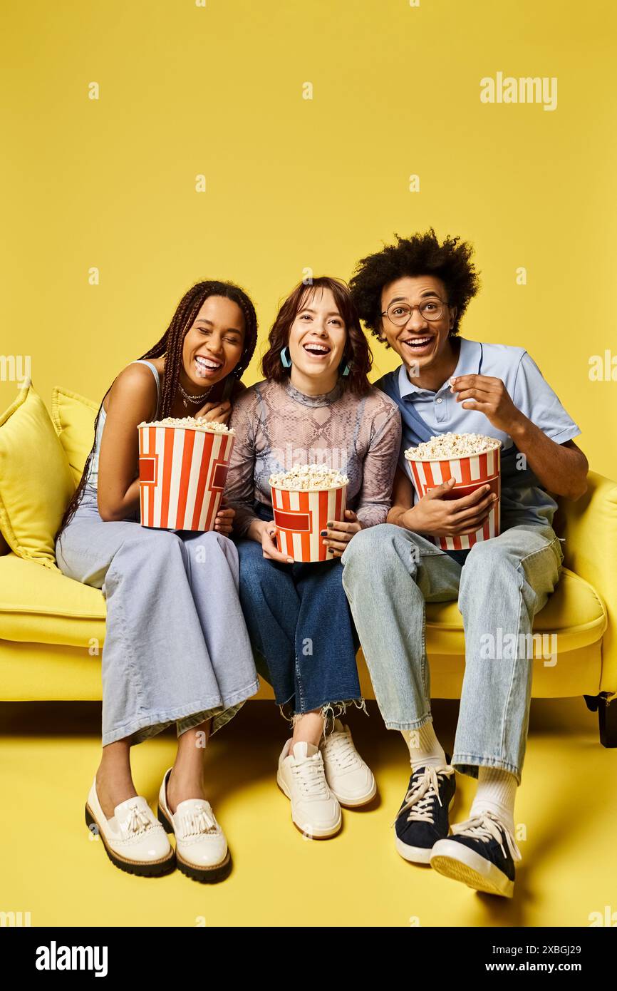 Young multicultural friends sitting on a couch, holding popcorn boxes ...