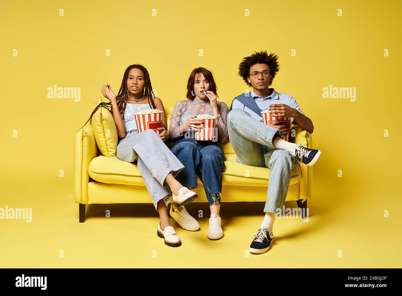 Three young friends of diverse backgrounds are lounging on a couch ...