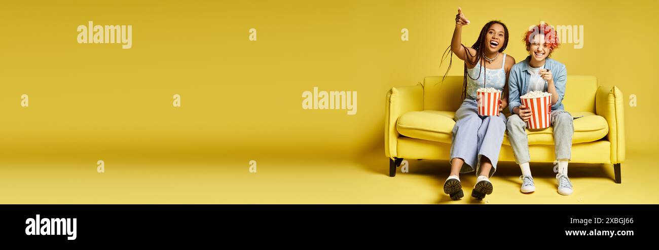 friends in stylish attire sit on a yellow chair, happily snacking on ...