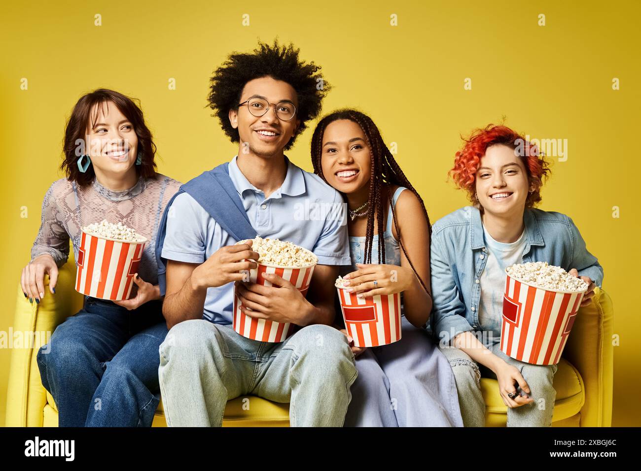 A diverse group of people sit together, holding buckets of popcorn in a ...