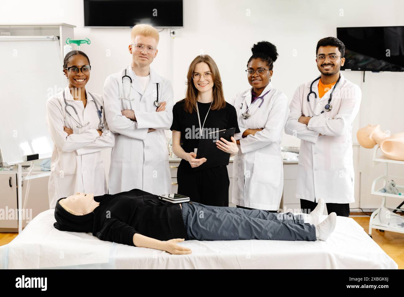 A group of five medical students stand around a training dummy ...