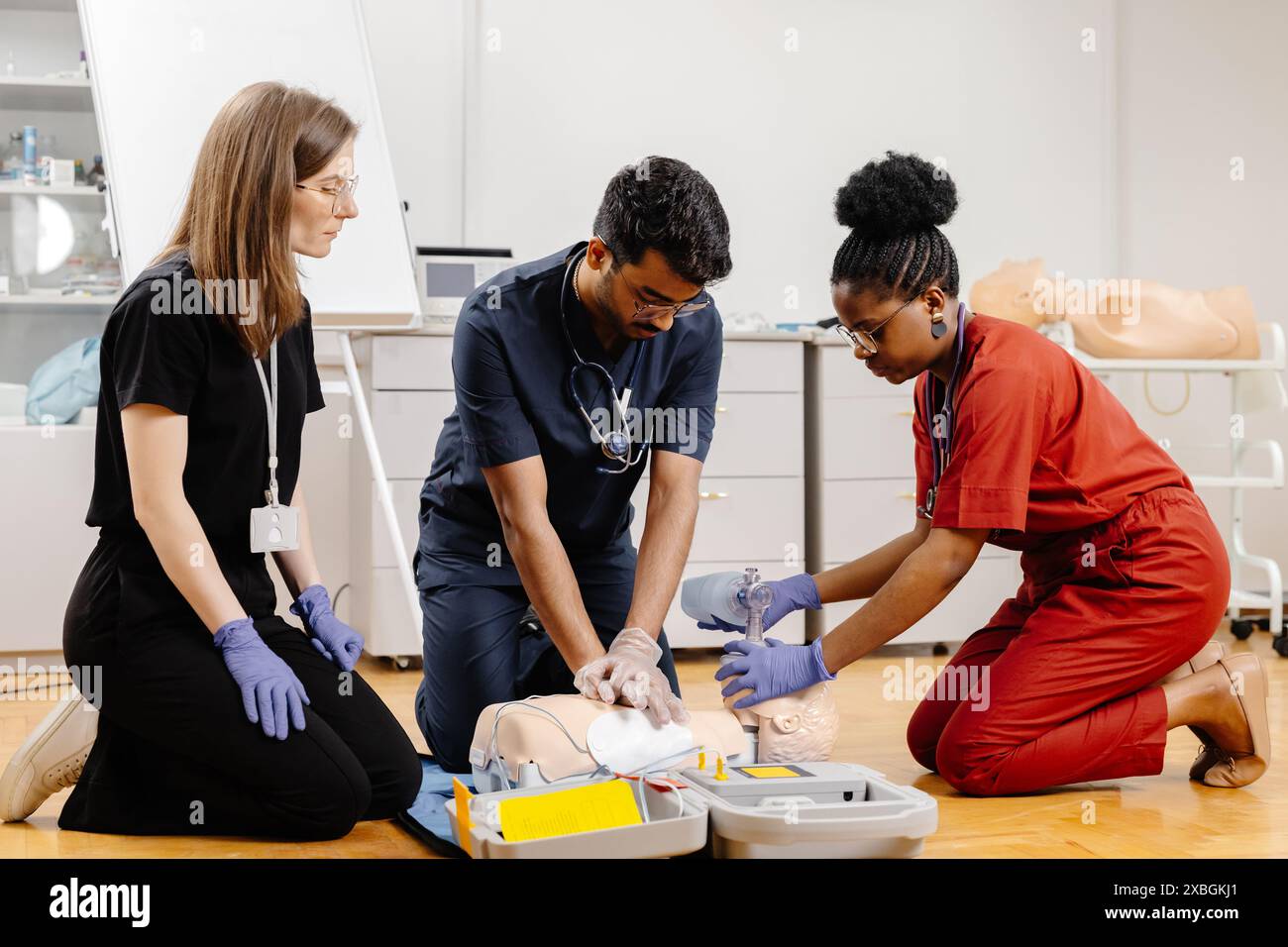Three medical professionals are practicing CPR on a training dummy ...